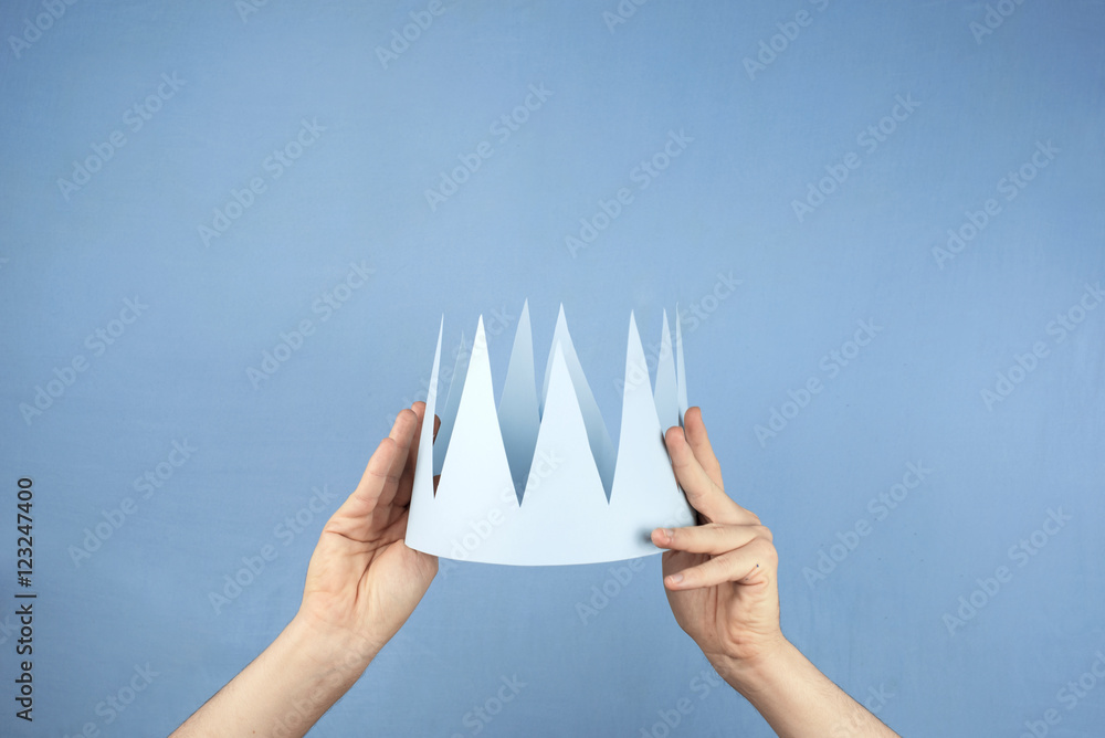 Escena minimalista de unas manos sujetando una corona, a punto de ...