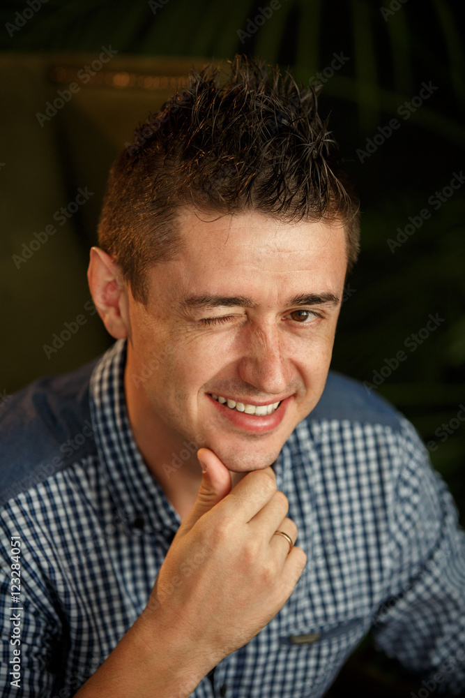 Emotion wink. Young man holds his chin and winks at the camera Stock ...