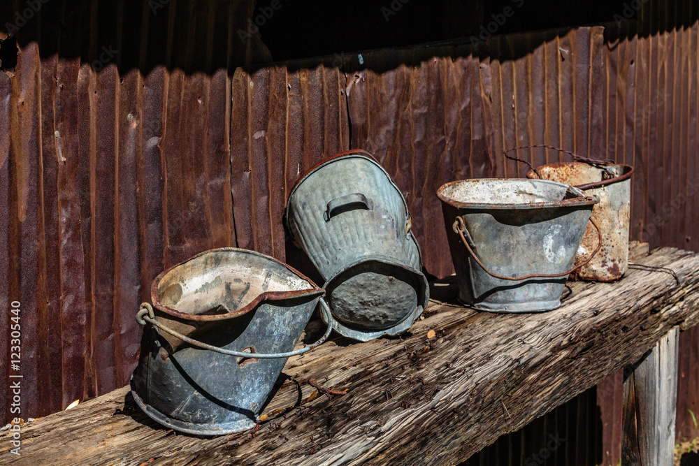 Rusted Antique Pails Lined Up Along an Old Wooden Bench at Faraway ...