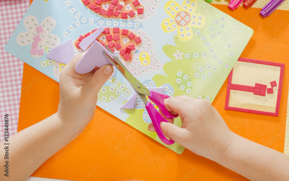 Poster Little child hands cutting paper with scissors on the art lesson ...