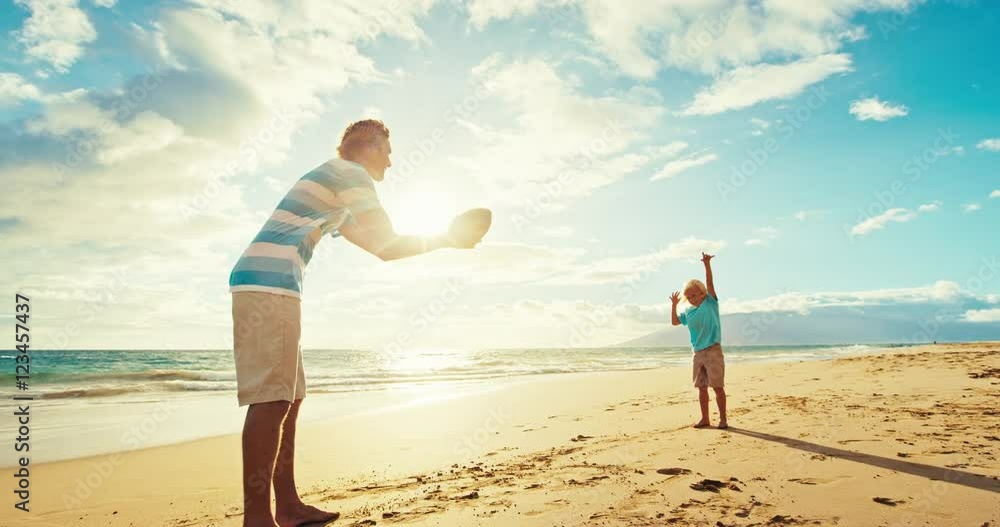 Father and son having fun on the beach at sunset, playing catch with ...