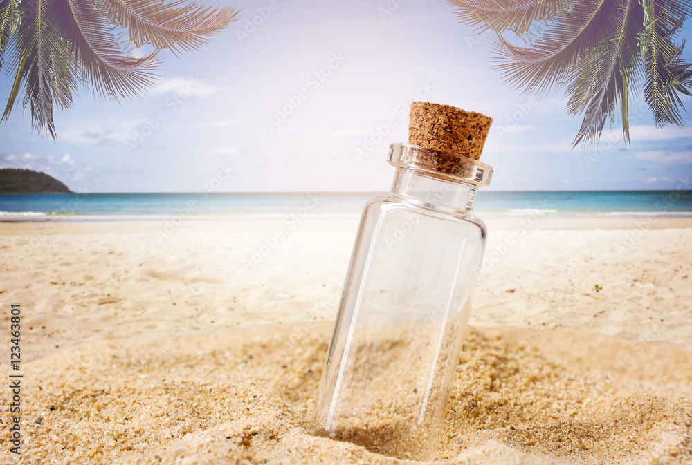 empty bottle over tropical sand beach with clear blue sky background ...