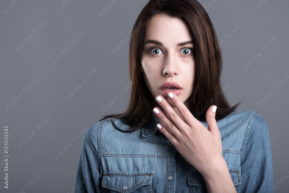 Scared young woman raising hand to her mouth Stock Photo | Adobe Stock