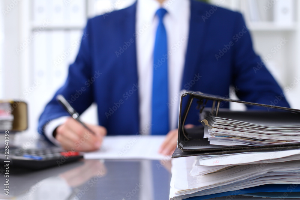 Binders with papers are waiting to be processed with businessman back ...