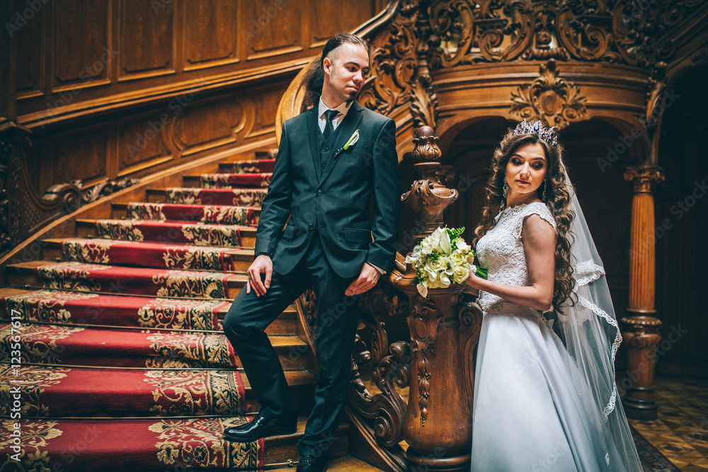 elegant gorgeous bride and stylish groom standing on wooden stairs in ...