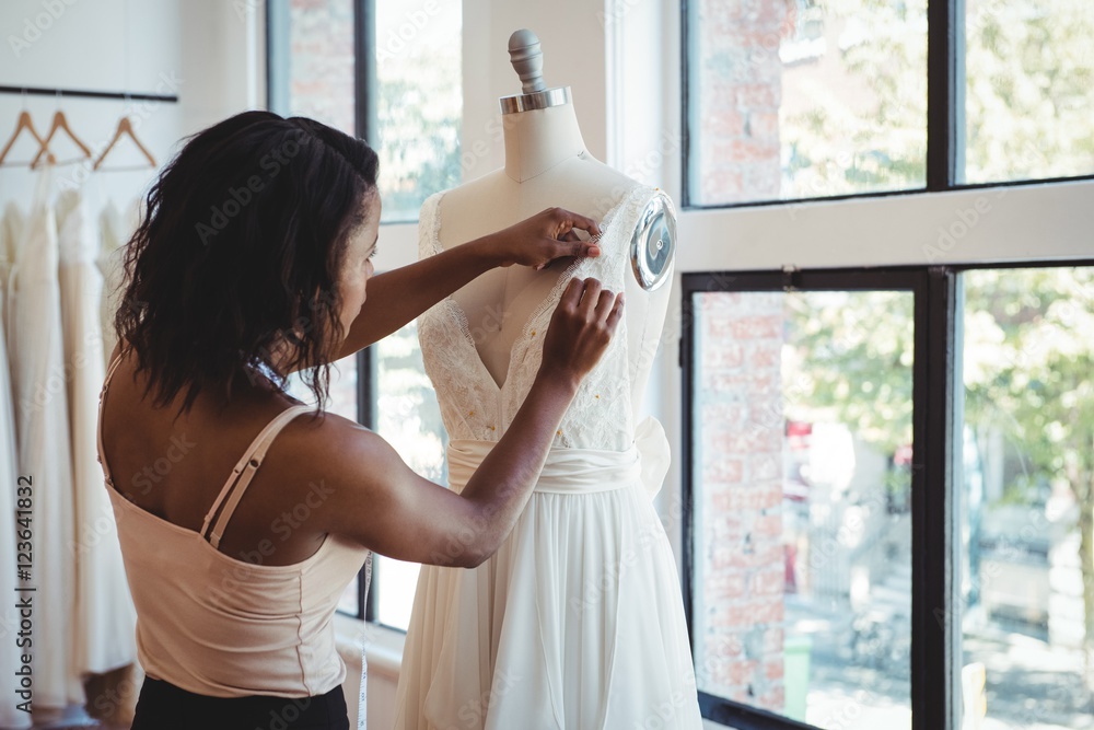 Female fashion designer adjusting the dress on mannequin Stock Photo ...