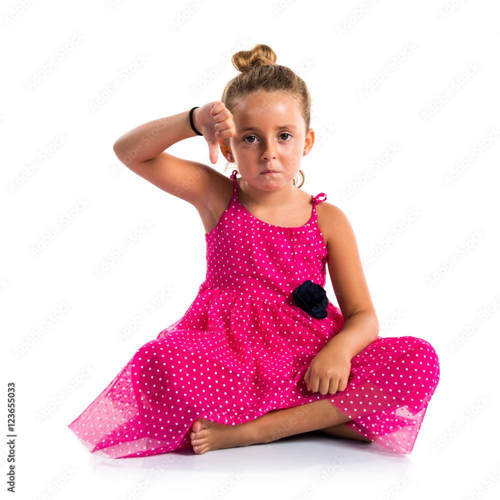 Little girl with pink dress doing bad signal Stock Photo | Adobe Stock