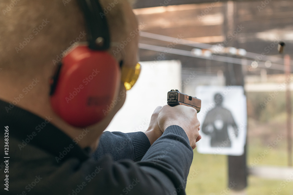Shooting with a pistol. Man aiming pistol in shooting range. Stock ...