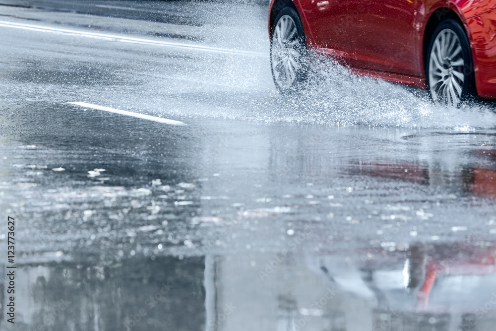 red car driving through water puddle with water splashing from its ...