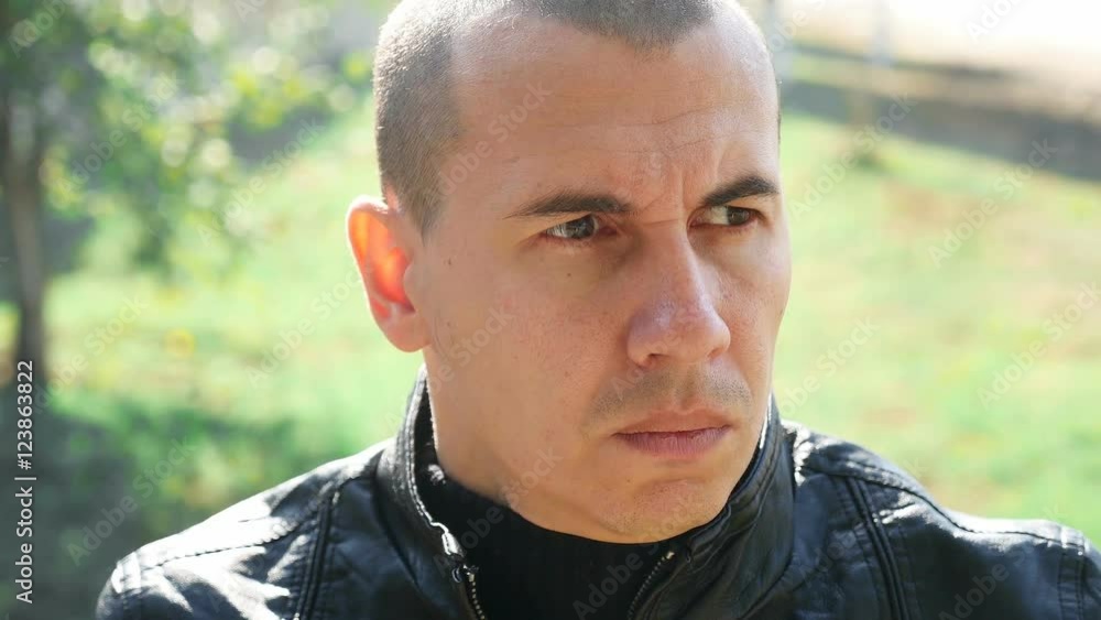 angry man thug unhappy in leather jacket in the background railway ...