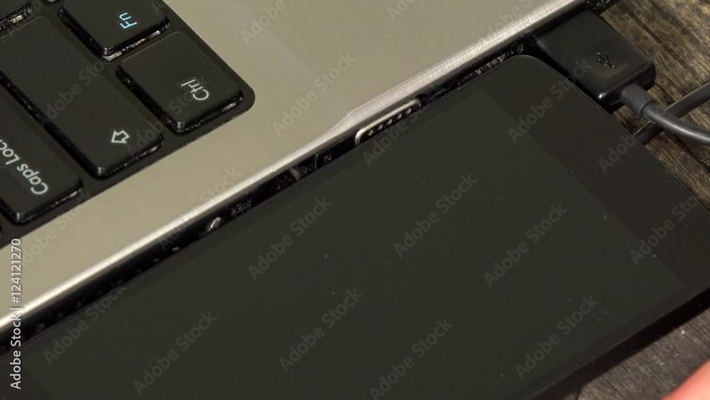 Hand place smart phone on wireless charger connected to laptop computer ...