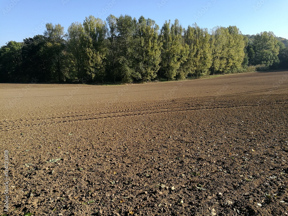 Braunes Erdreich mit Traktorenspuren auf einem gepflügten Acker und ...