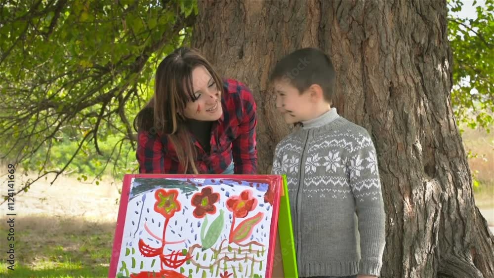 Little paintert shows mom how to draw pictures. Mother and son paint on ...