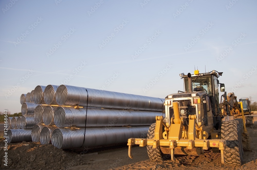 Road Construction Using A Grader And A Bundle Of Culvert Pipes ...