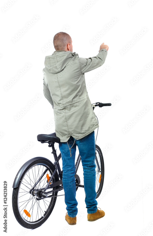 back view of pointing man with a bicycle. Cyclist in parka jacket keeps ...
