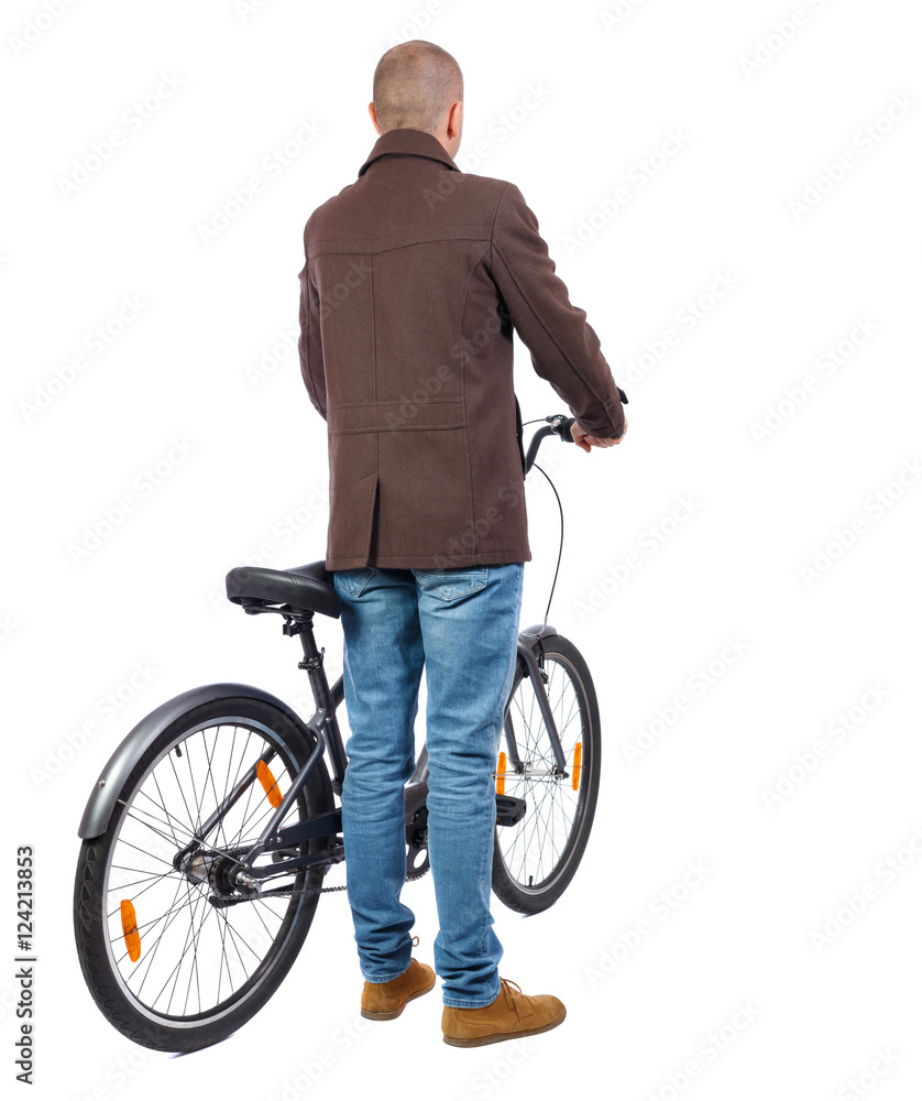 back view of a man with a bicycle. Cyclist in coat jacket keeps the ...