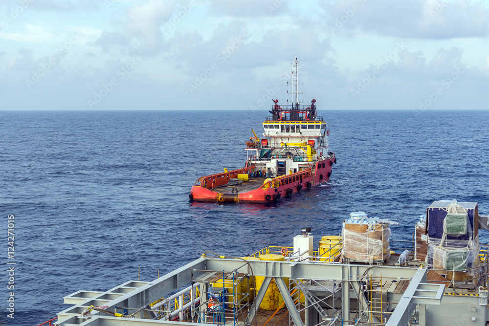 Anchor handling tug boat at the back of construction barge in the ...