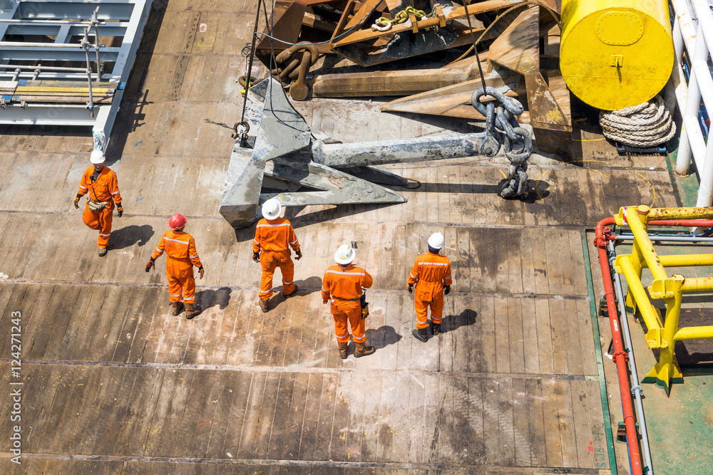 Offshore crews handling and lifting anchor for deployment on ...