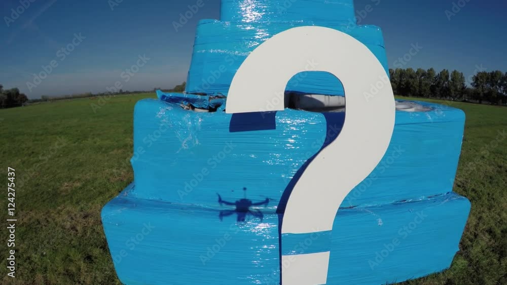 Aerial of white question mark on small bright blue structure drone ...