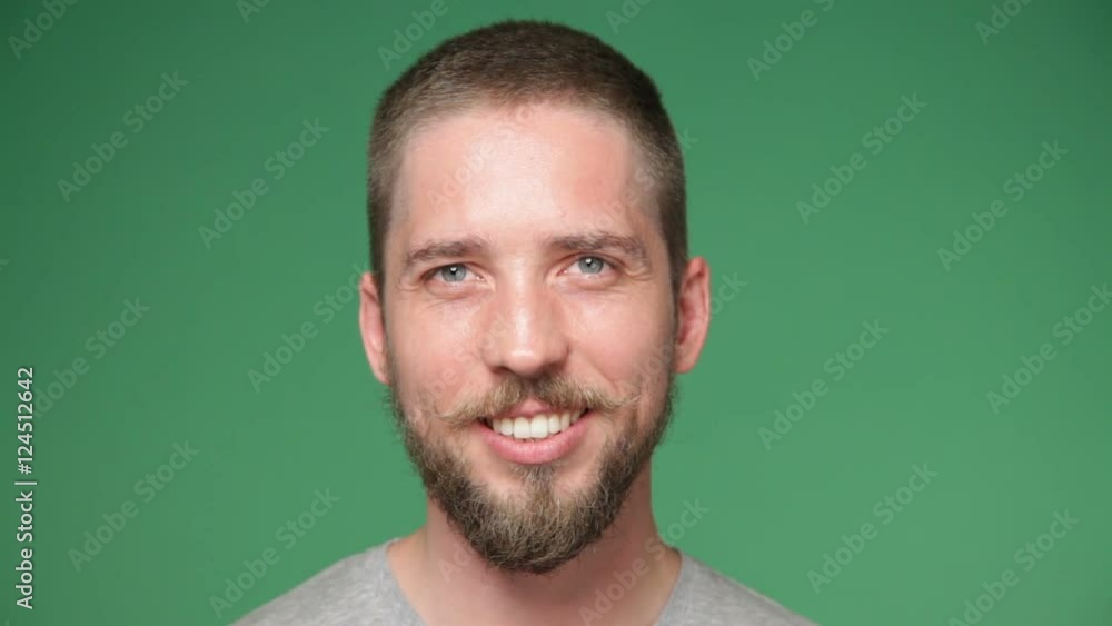 Close up young hipster man with mustache and beard smiling against ...