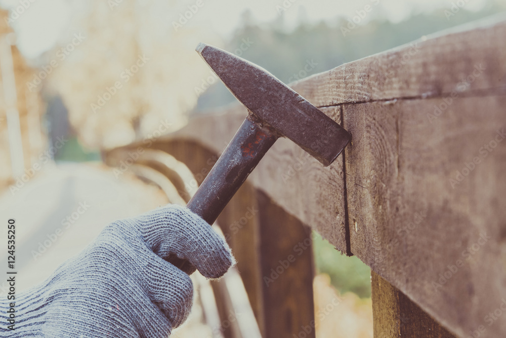 Carpenter's hands beating nails with an old iron hammer in sunny ...