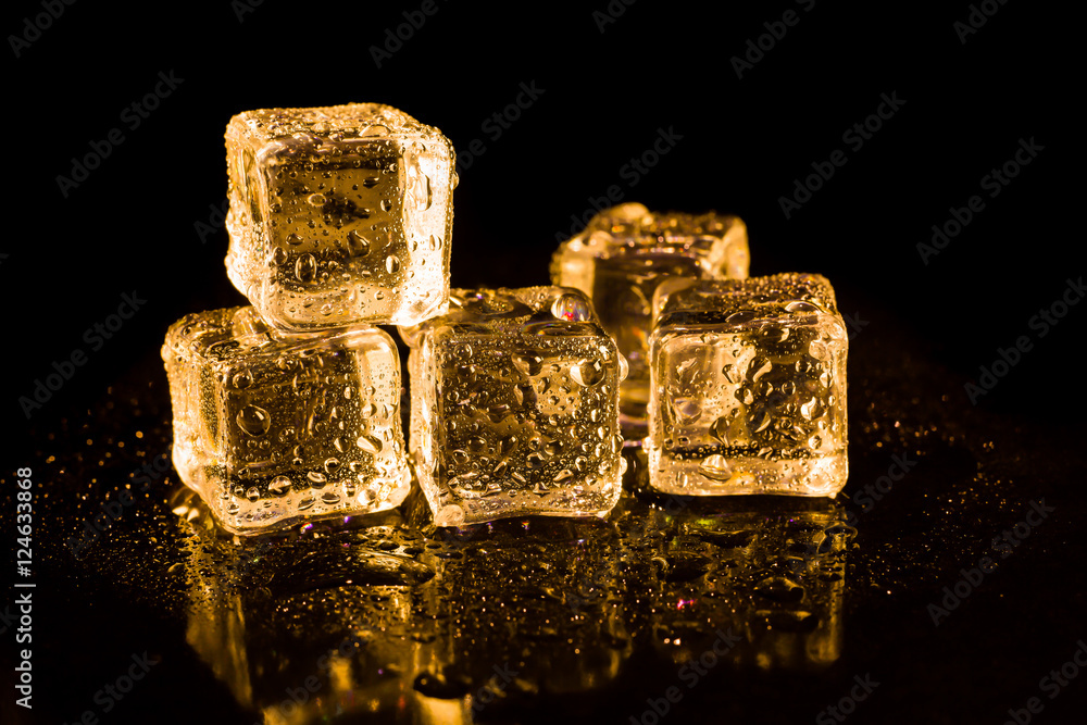 Ice cubes of gold color on a reflective surface. Stock-Foto | Adobe Stock