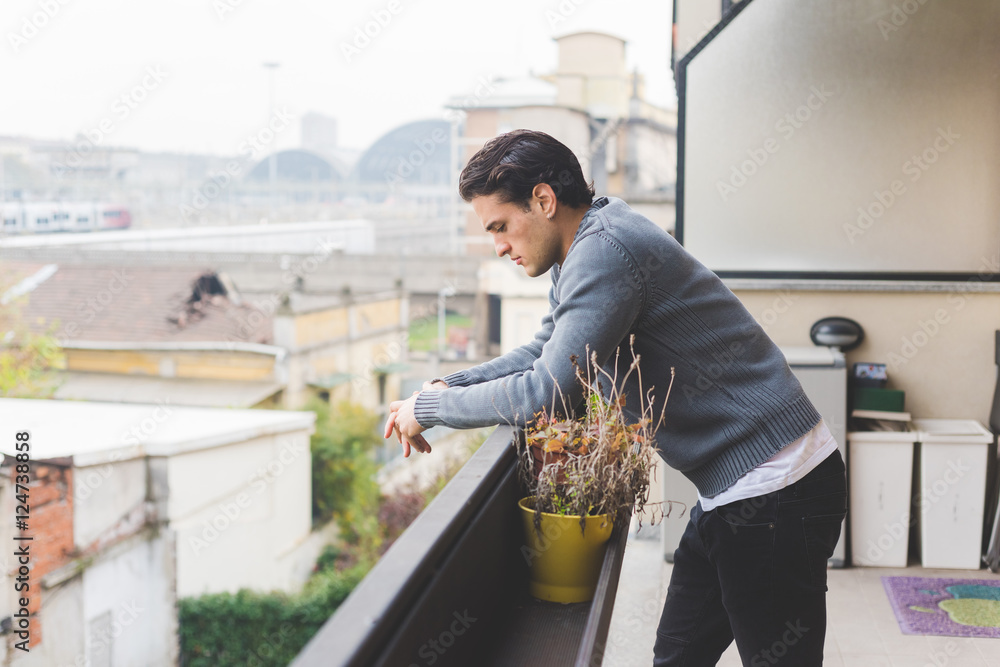 Half length of young handsome man standing on a balcony outdoor ...