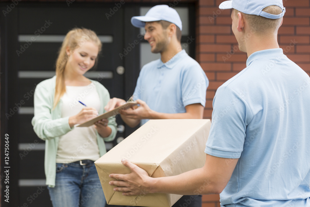 Courier with package and woman signing a form Stock Photo | Adobe Stock