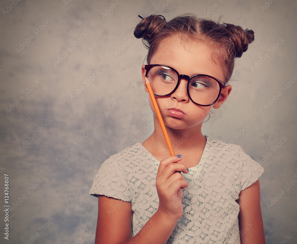 Thinking grimacing kid girl in glasses looking and holding penci Stock ...