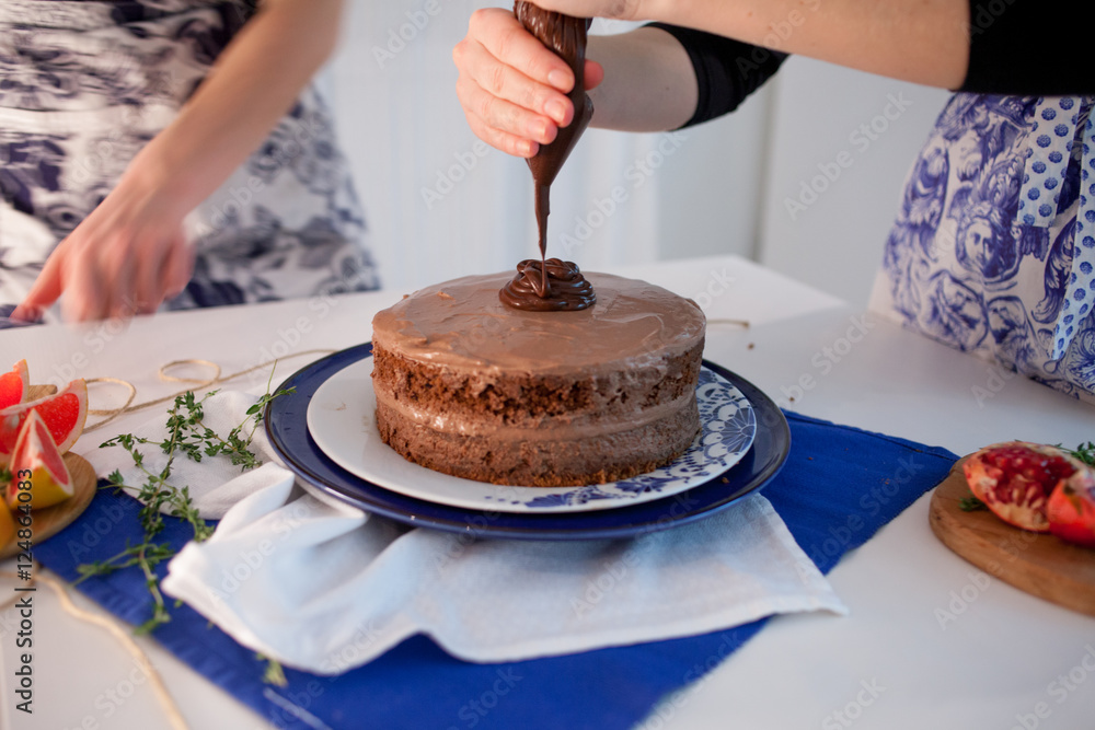 Two girls making a cake on the kitchen. Female hand squeezes the ...