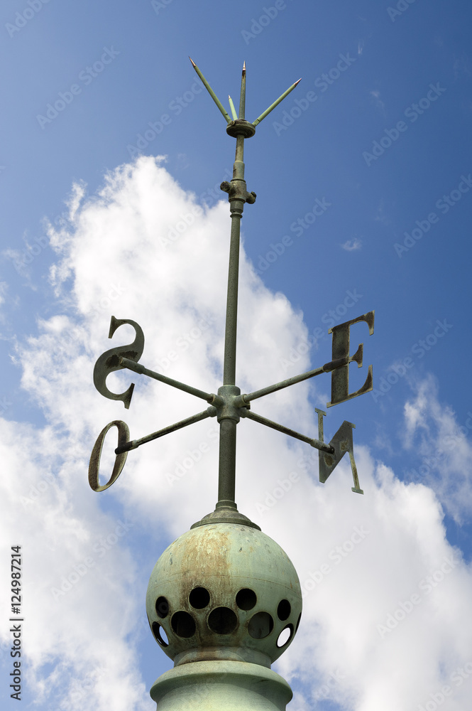 Old cardinal points on a roof with a lightning rod on blue sky with ...