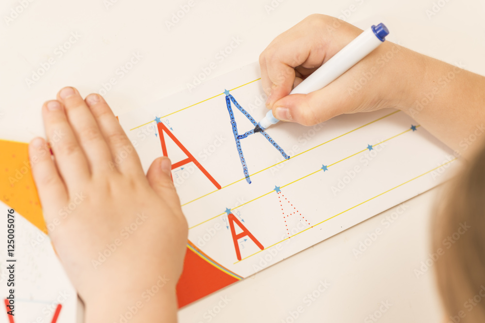 Little child hands writing letter A. Learning to write. Little girl ...