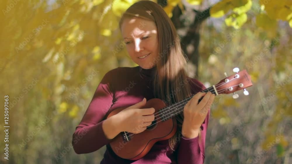 Young Beautiful Girl Playing Ukulele Guitar and Singing in Autumn ...