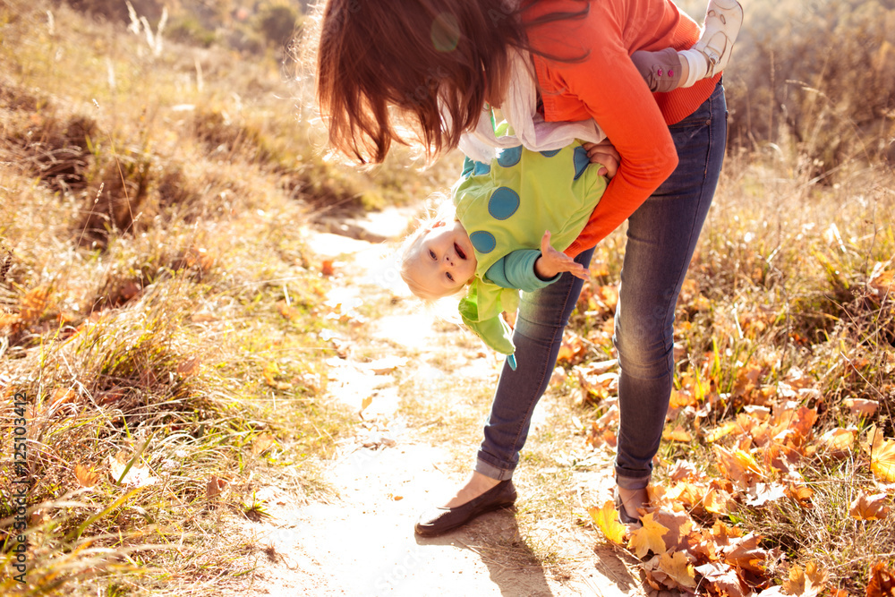 Mom in orange pullover bends over her little daughter Stock Photo ...