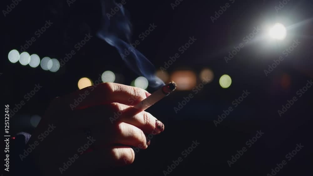 Girl hand holding a cigarette while smoking at night. Closeup of a ...