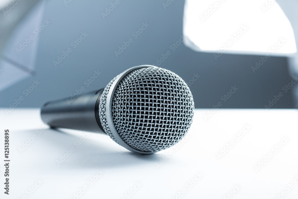 A microphone lying on a white table. Against the background of studio ...
