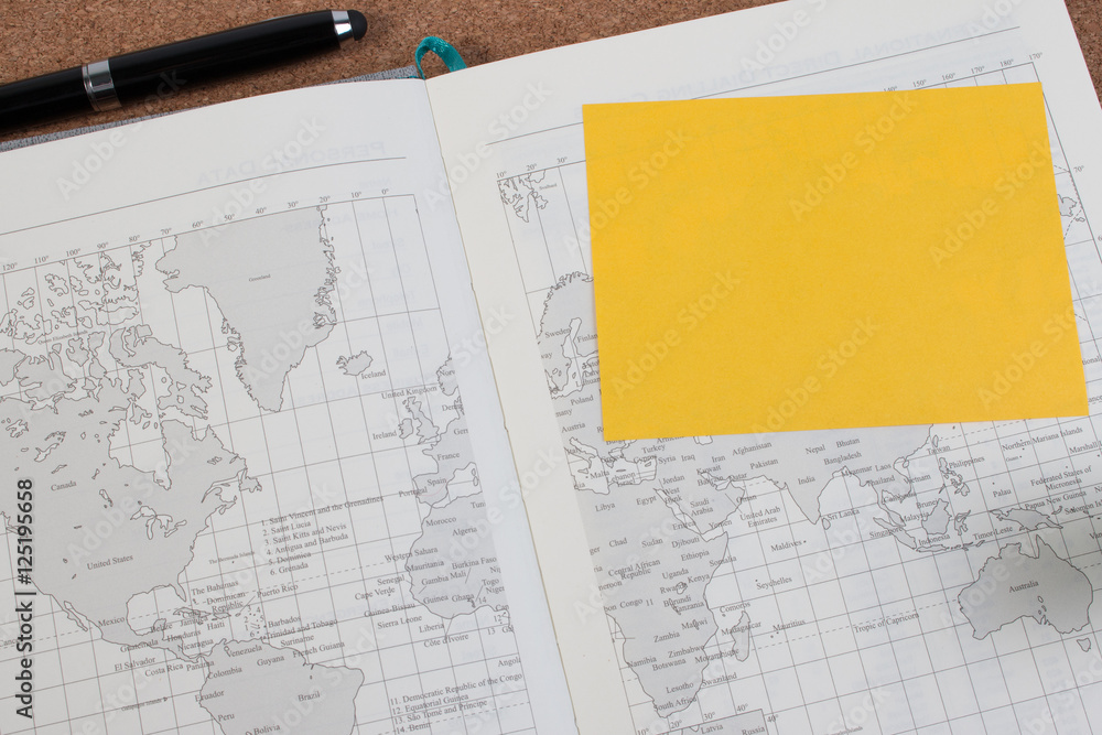 World atlas diary book with yellow paper note. Open diary map book with ...