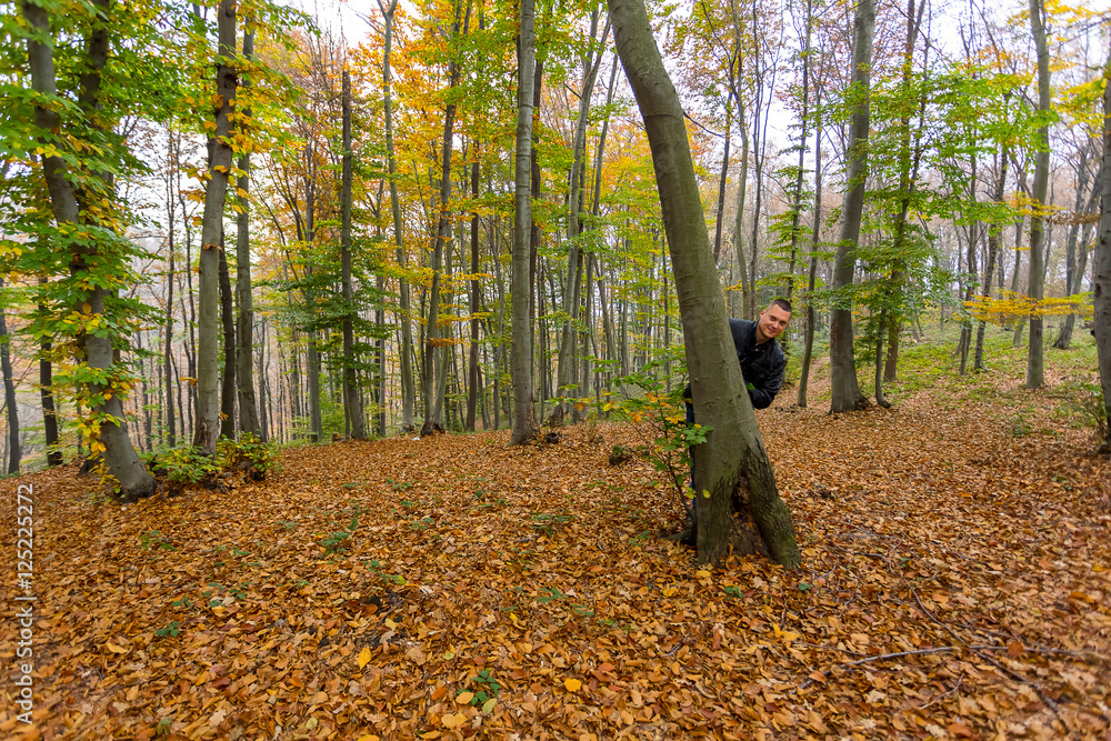 man hiding behind the tree in the forest 스톡 사진 | Adobe Stock