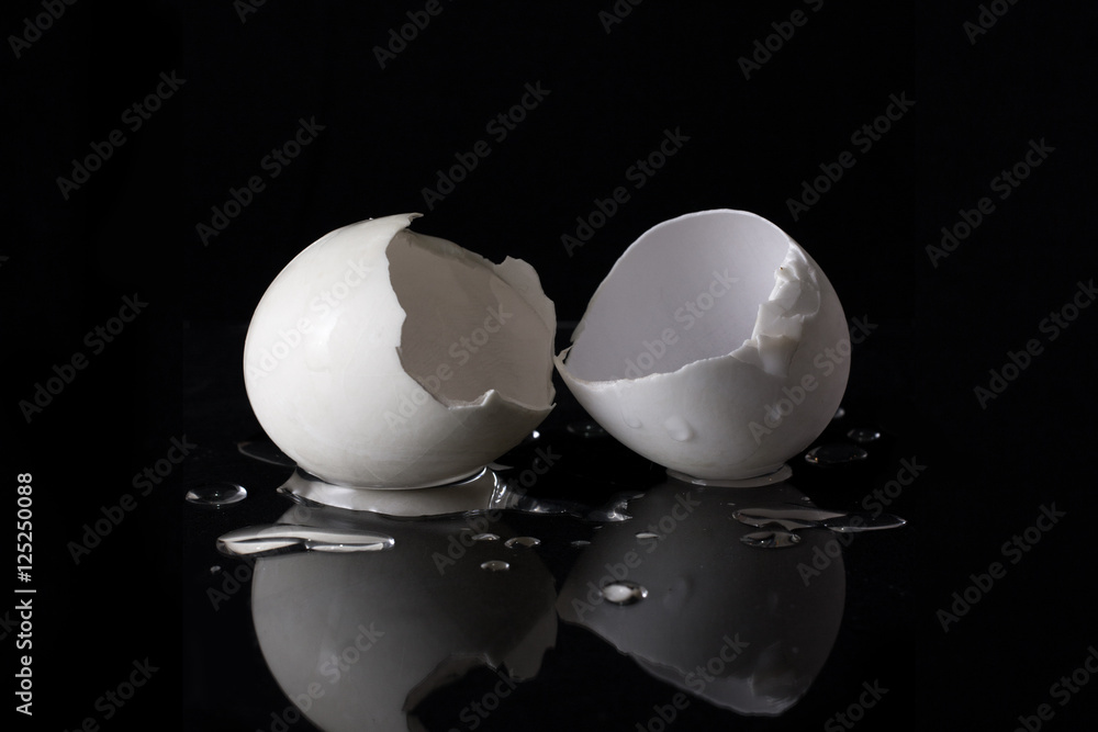 Cracked white egg shells isolated on black background with water drop ...