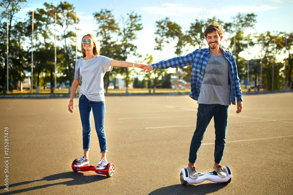 young man and woman riding on the Hoverboard in the park. content ...