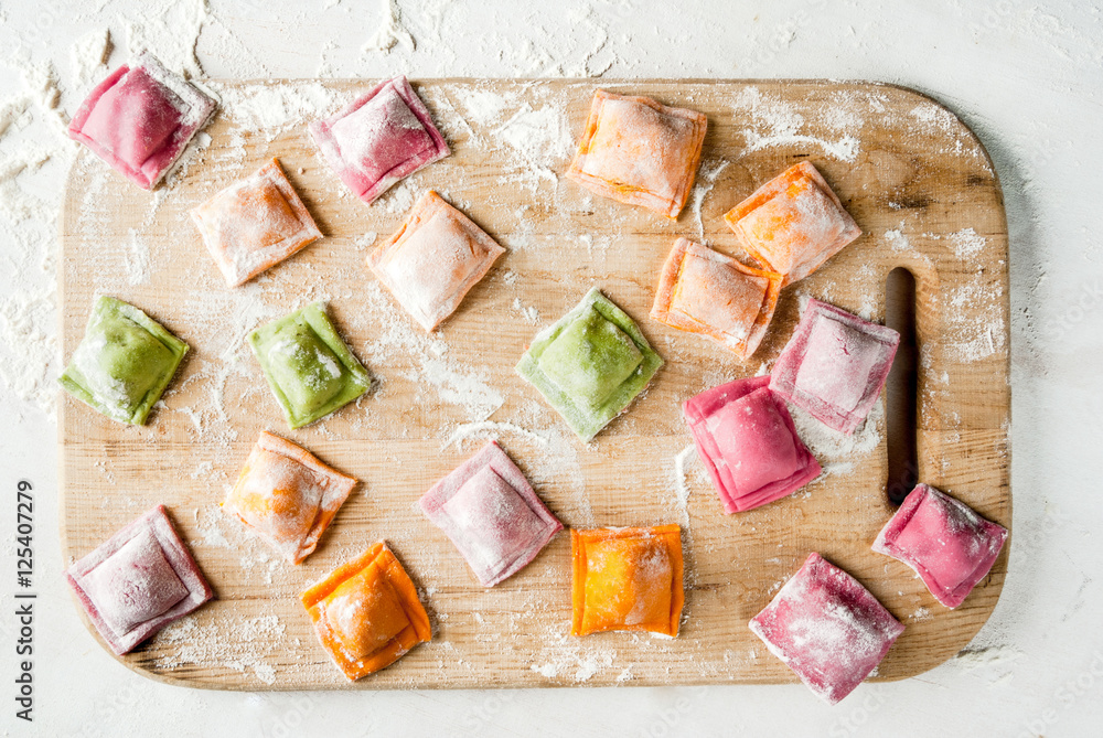 Multi-colored ravioli on a cutting board, sprinkled with flour, cooking ...