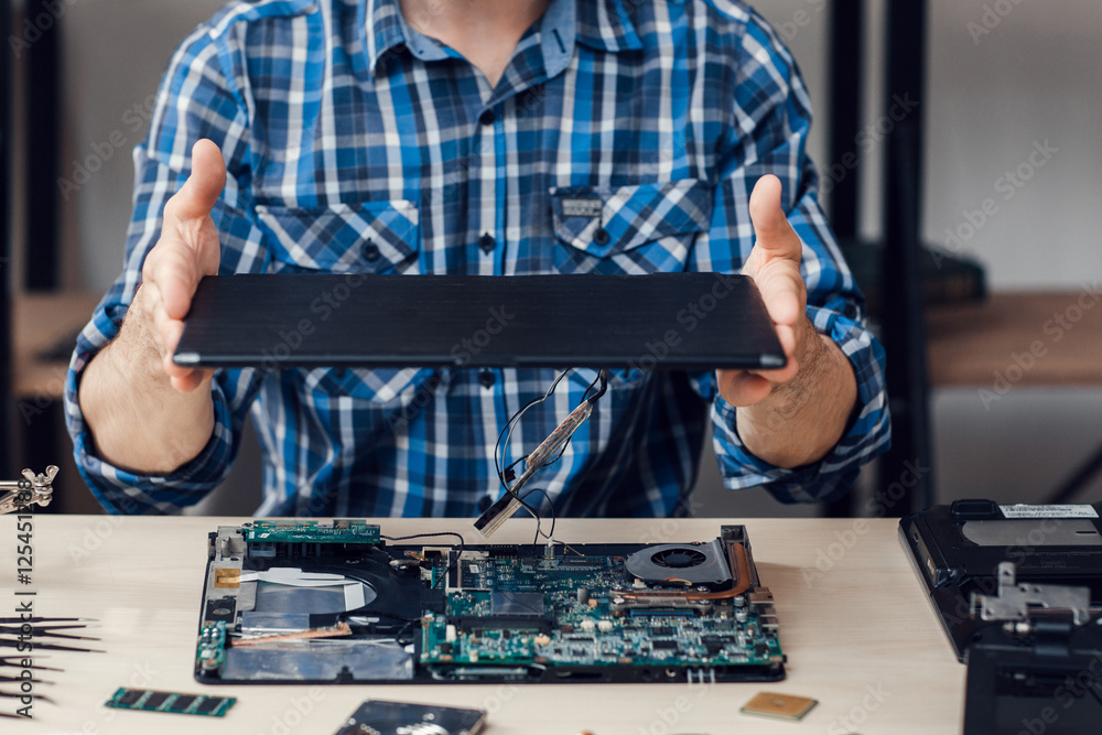 Laptop disassembling at electronic repair shop. Unrecognizable engineer ...
