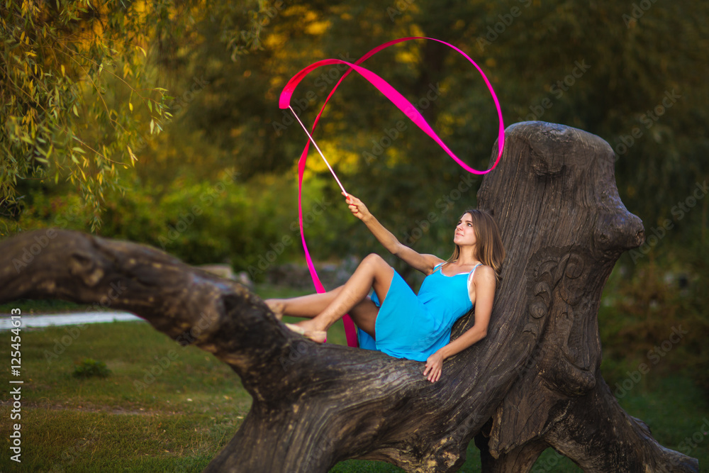 Beautiful sweet young girl sitting on a tree in the forest. She is ...