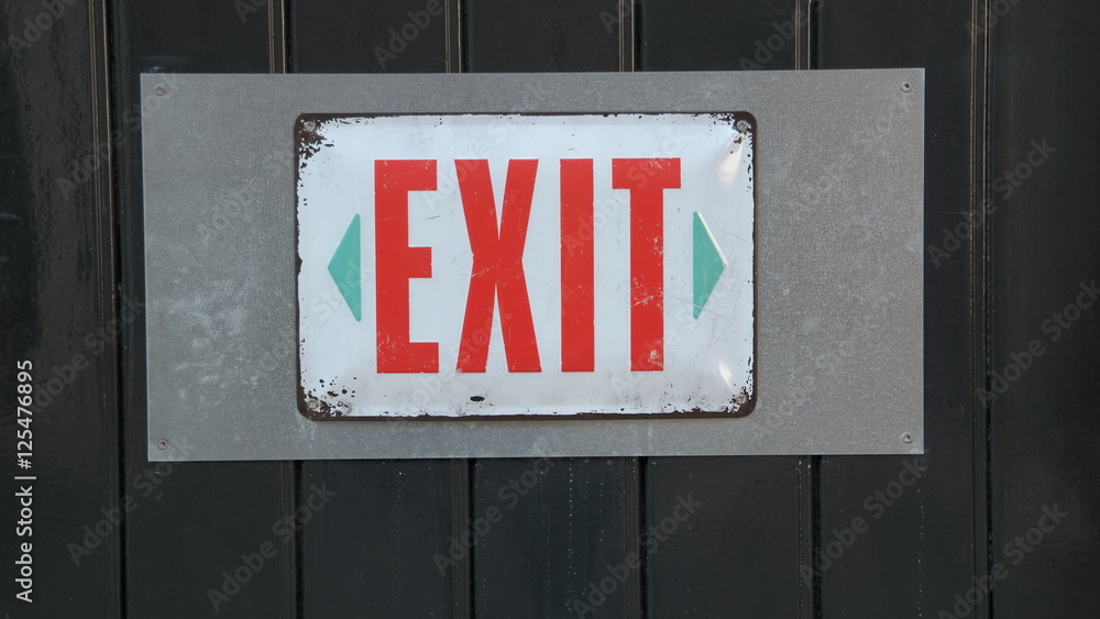 An old metal white exit sign. With red letters and made of tin. A ...