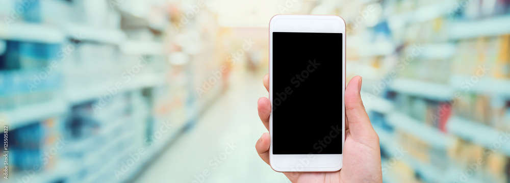 Female hand holding mobile phone with supermarket background Stock ...