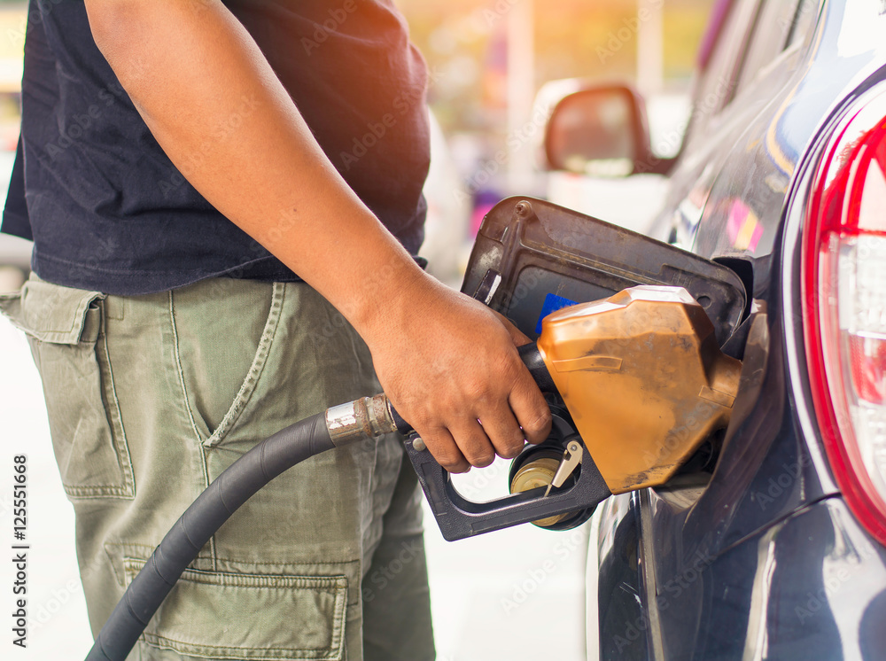Hand holding fuel to add gas at petrol station. Stock Photo | Adobe Stock