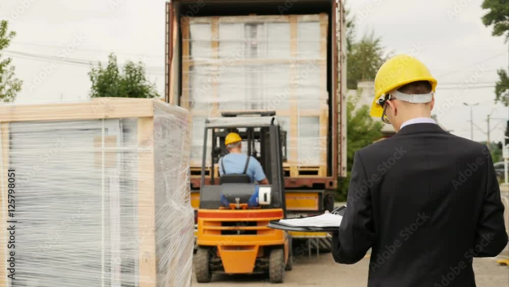 Loading cargo on a container with a forklift under the supervision of ...