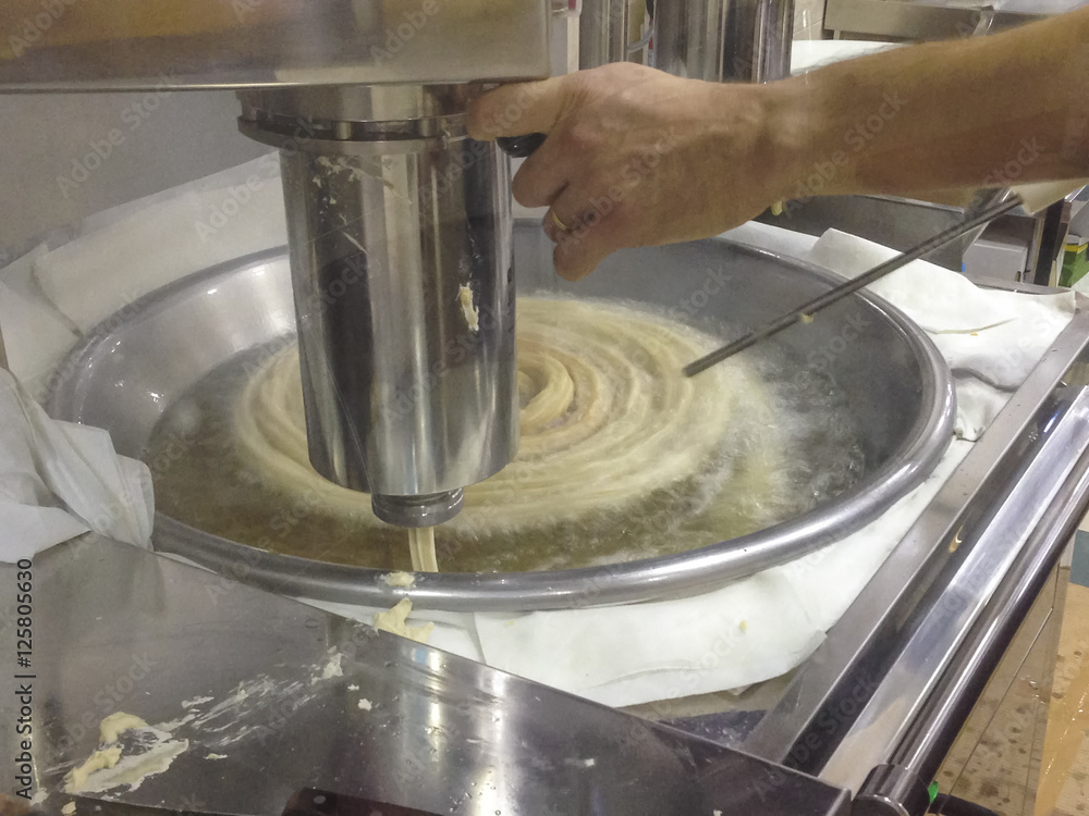Churros elaboration process. Churros maker fry pastry dought in spiral ...