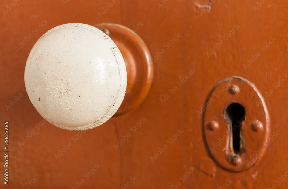 Old door knob and keyhole - An old white door knob and keyhole on a ...