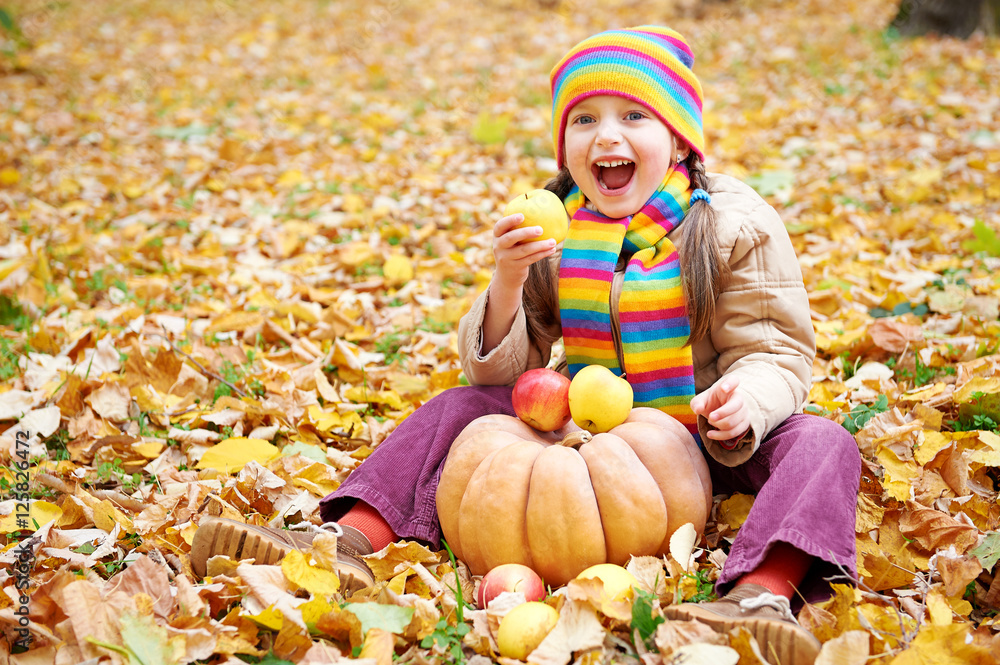 girl child in autumn forest, sit on yellow leaves, eat apple and ...